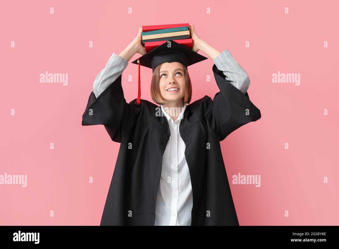 Female graduating student with books on color background Stock Photo ...