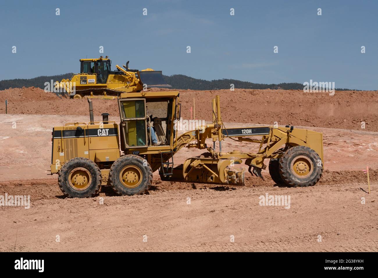 A Caterpillar motor grader and Komatsu crawler bulldozer move dirt at a ...