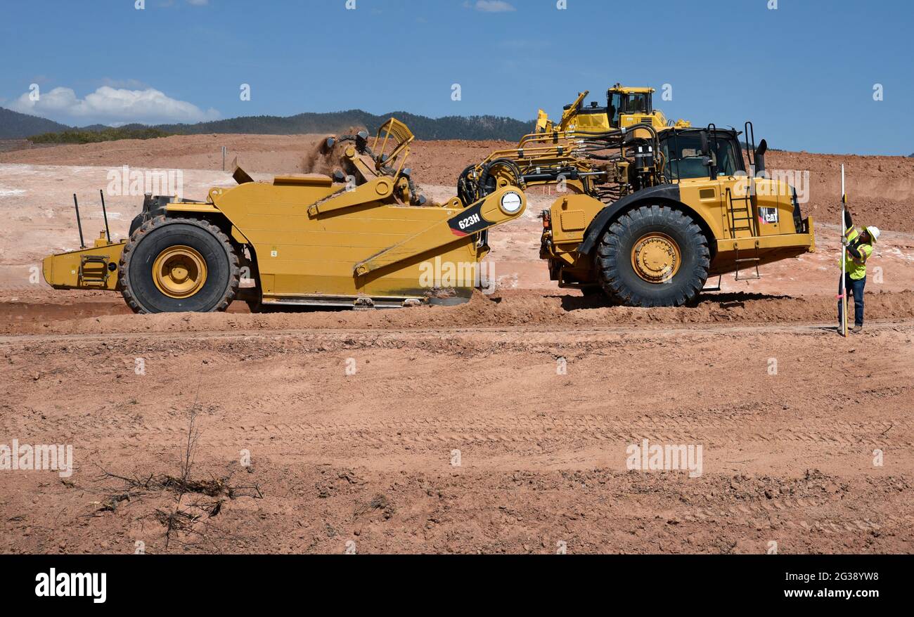 A Caterpillar wheel tractor-scraper moves dirt at a highway improvement ...
