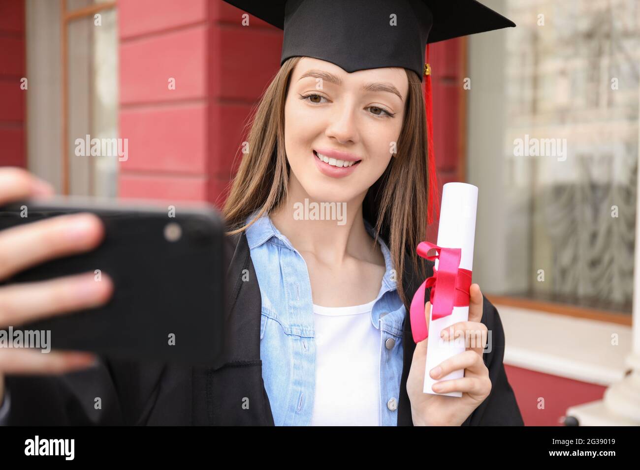 Female graduating student in bachelor robe taking selfie on her ...