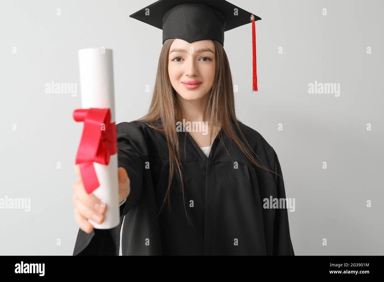 Female graduating student with diploma on light background Stock Photo ...