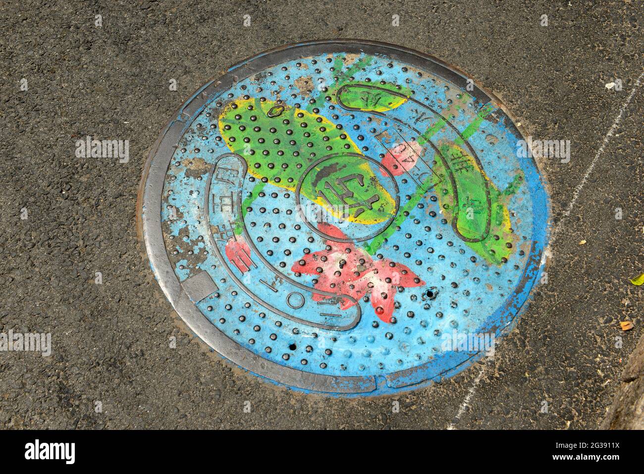 Manhole access cover on a street painted with marine images in Qingdao ...