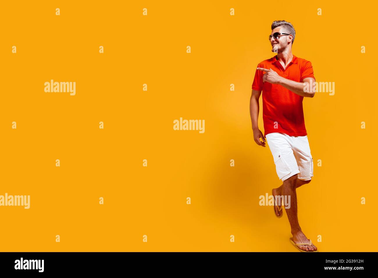 Full length portrait of a handsome man in shorts and red shirt walking ...