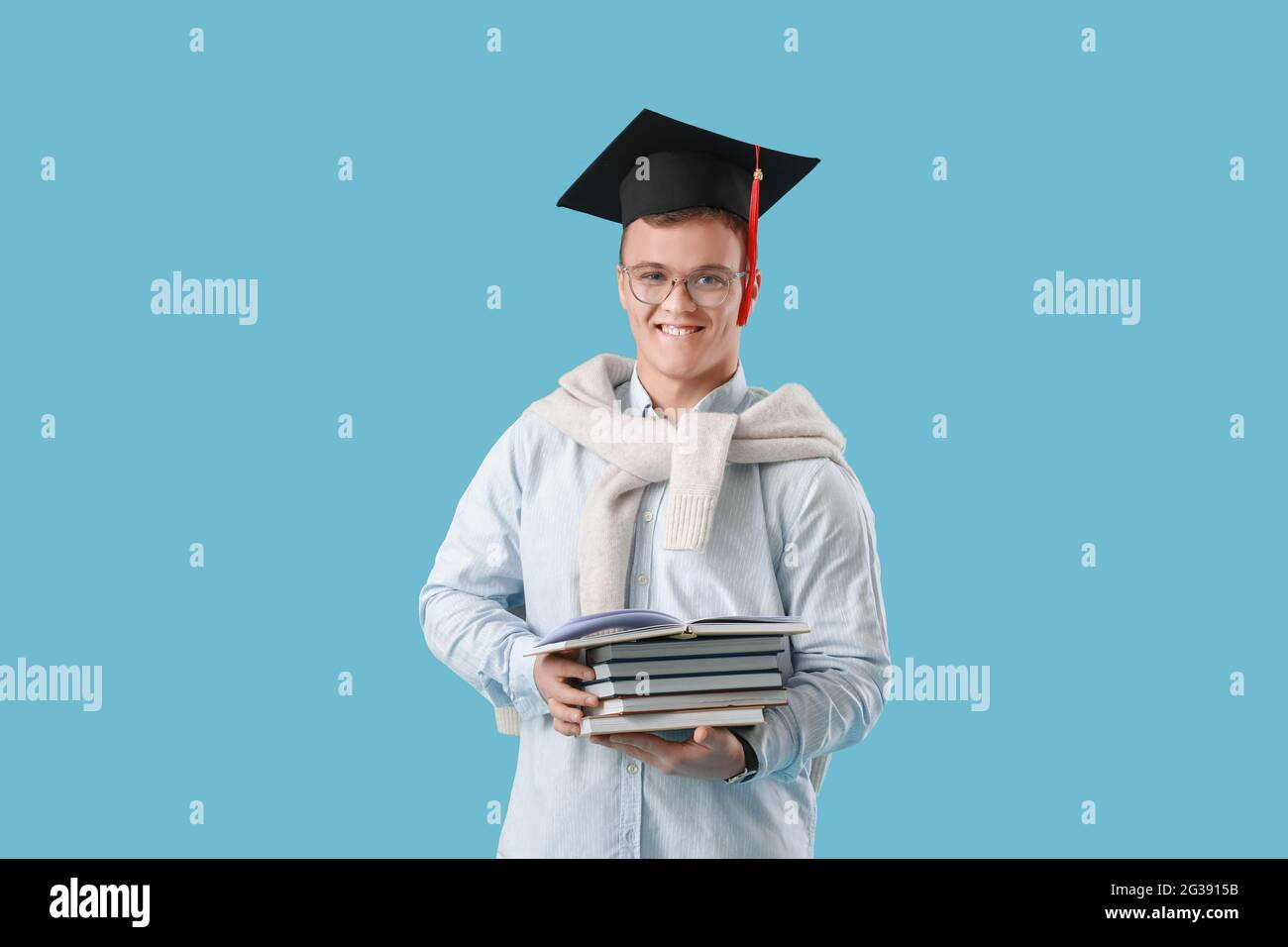 Male graduating student with books on color background Stock Photo - Alamy