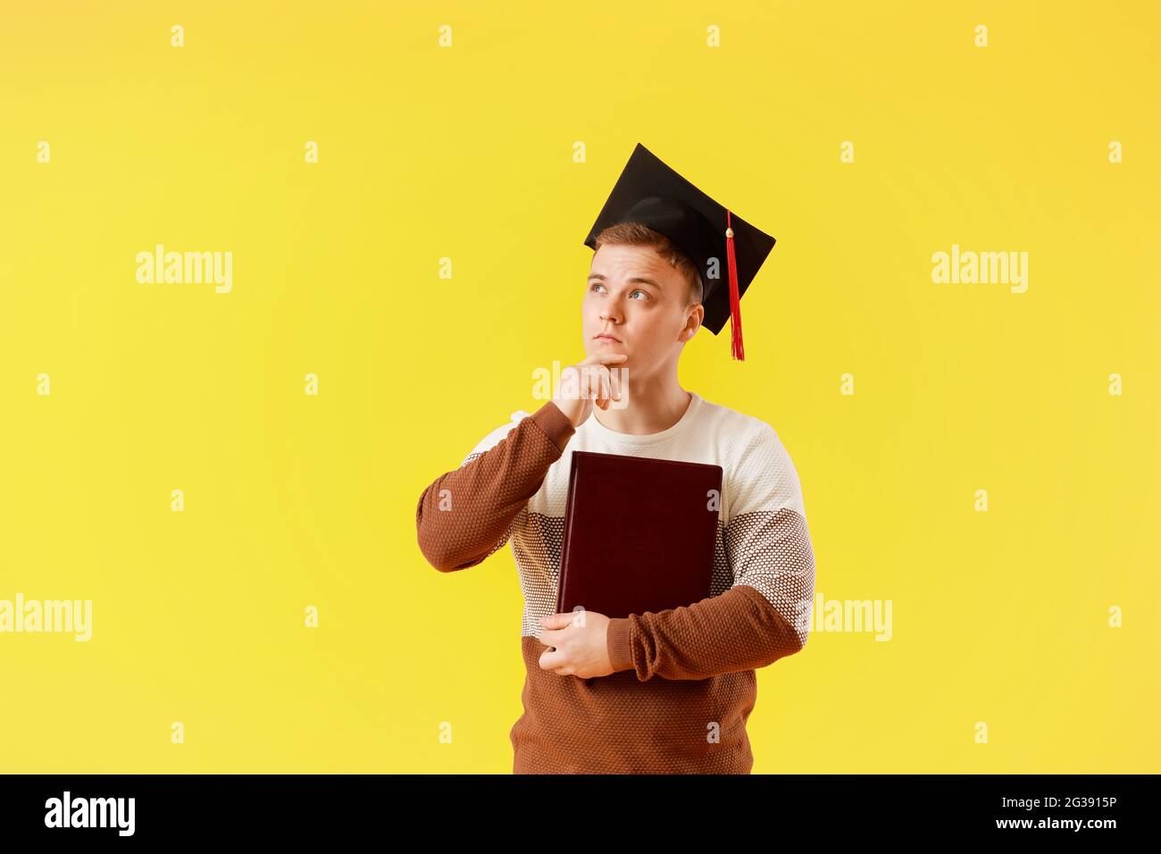 Thoughtful graduating student on color background Stock Photo - Alamy