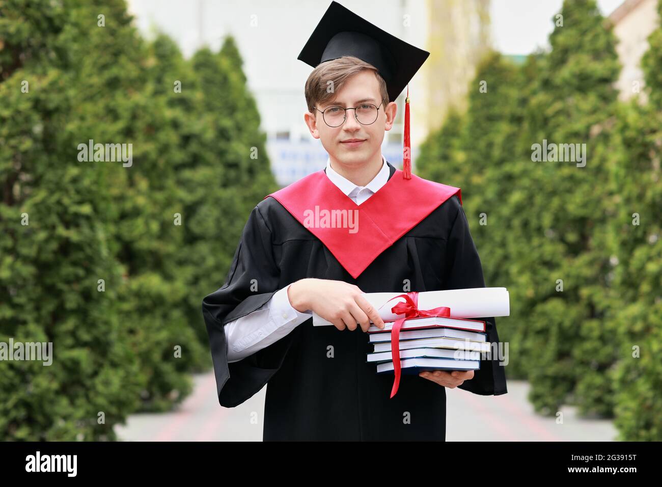 Portrait of male graduating student with books outdoors Stock Photo - Alamy