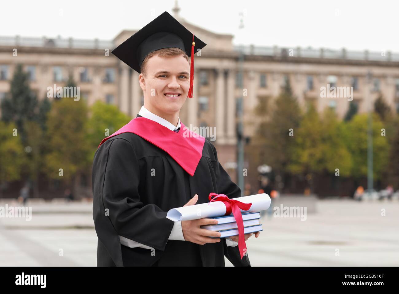 Portrait of male graduating student with books outdoors Stock Photo - Alamy