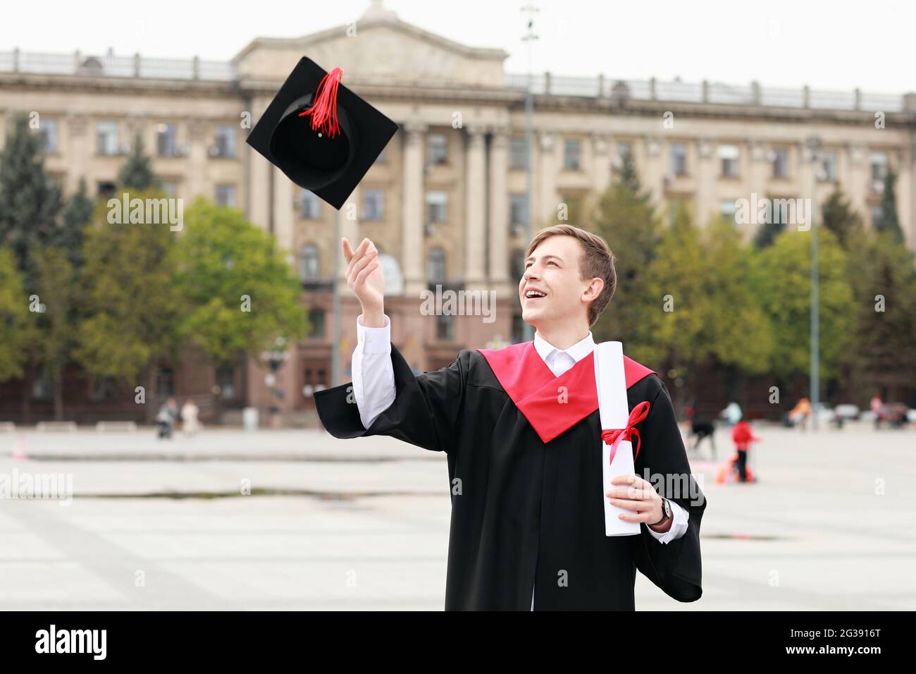 Portrait of male graduating student throwing cap outdoors Stock Photo ...