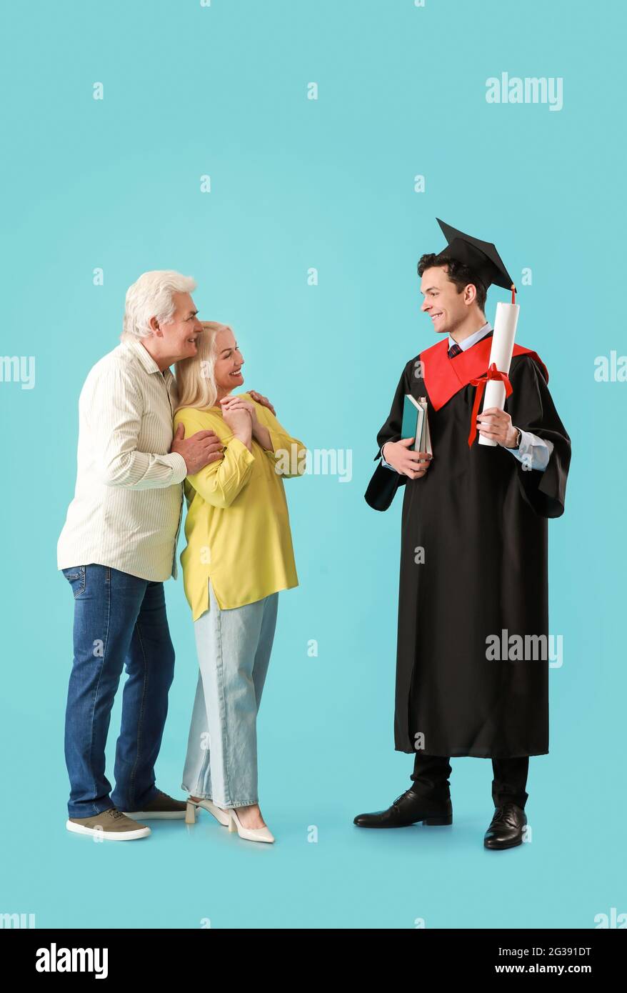 Happy male graduation student with his parents on color background ...
