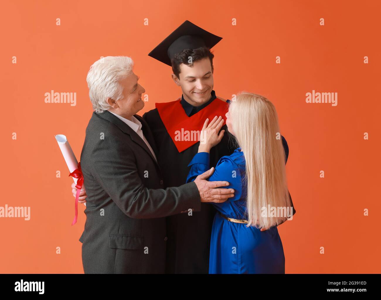 Happy male graduation student with his parents on color background ...