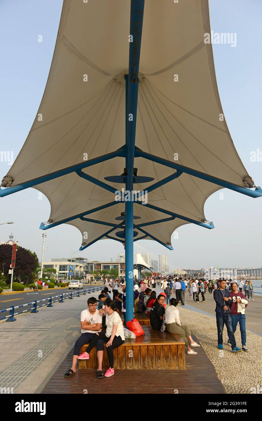 Visitors take a rest at a shady sitting area on the seafront near ...