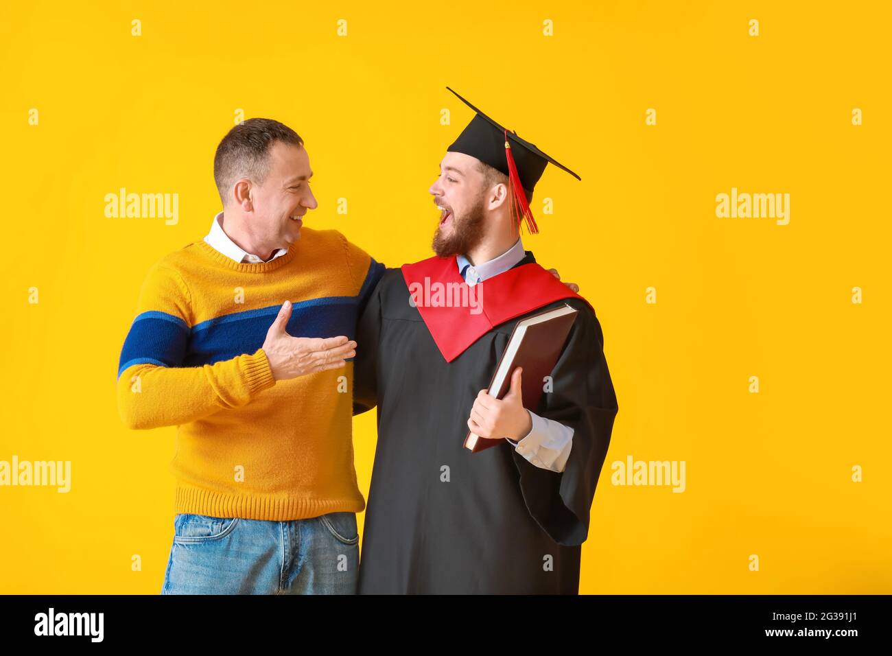 Happy male graduation student with his father on color background Stock ...