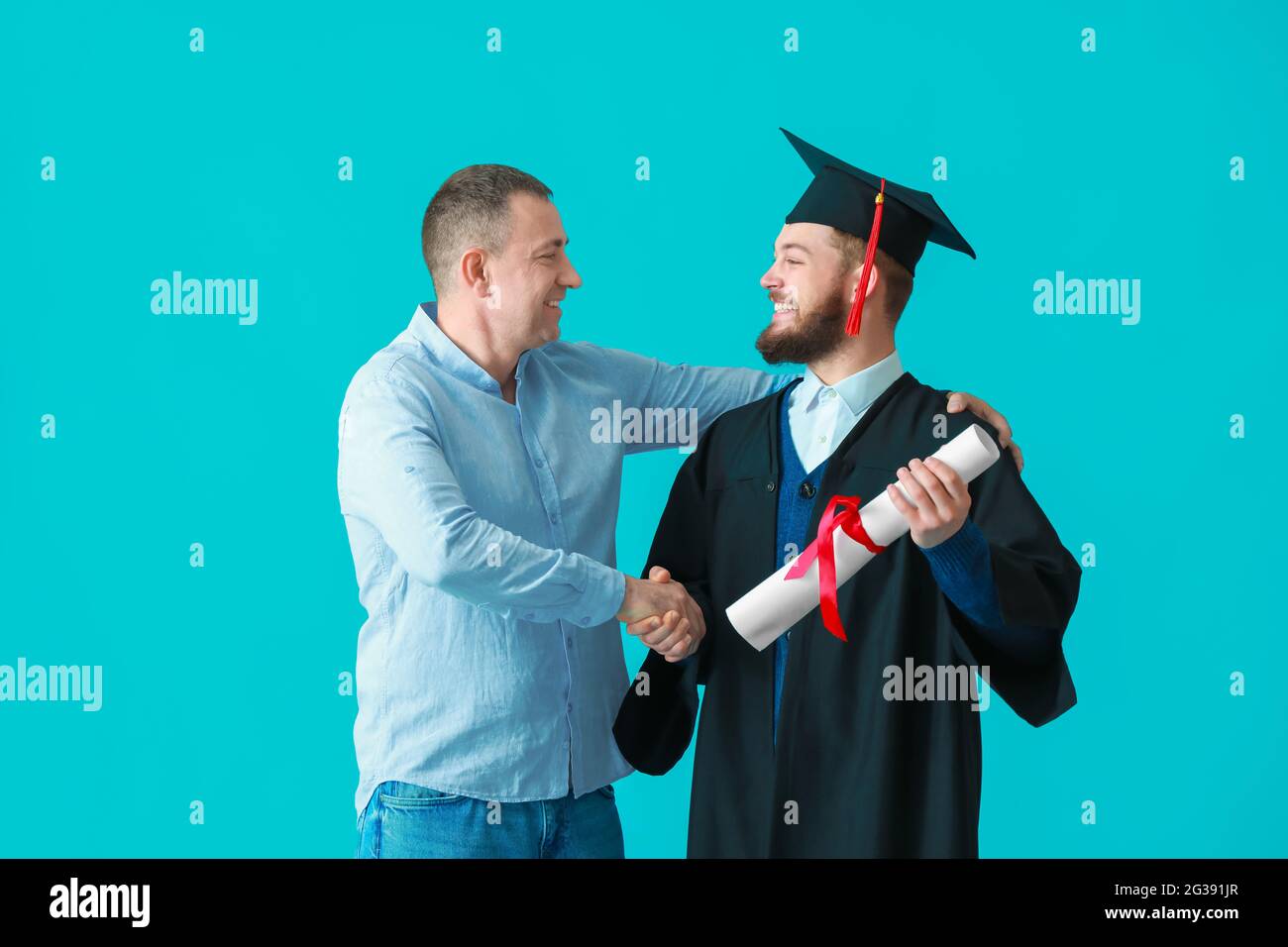 Happy male graduation student with his father on color background Stock ...