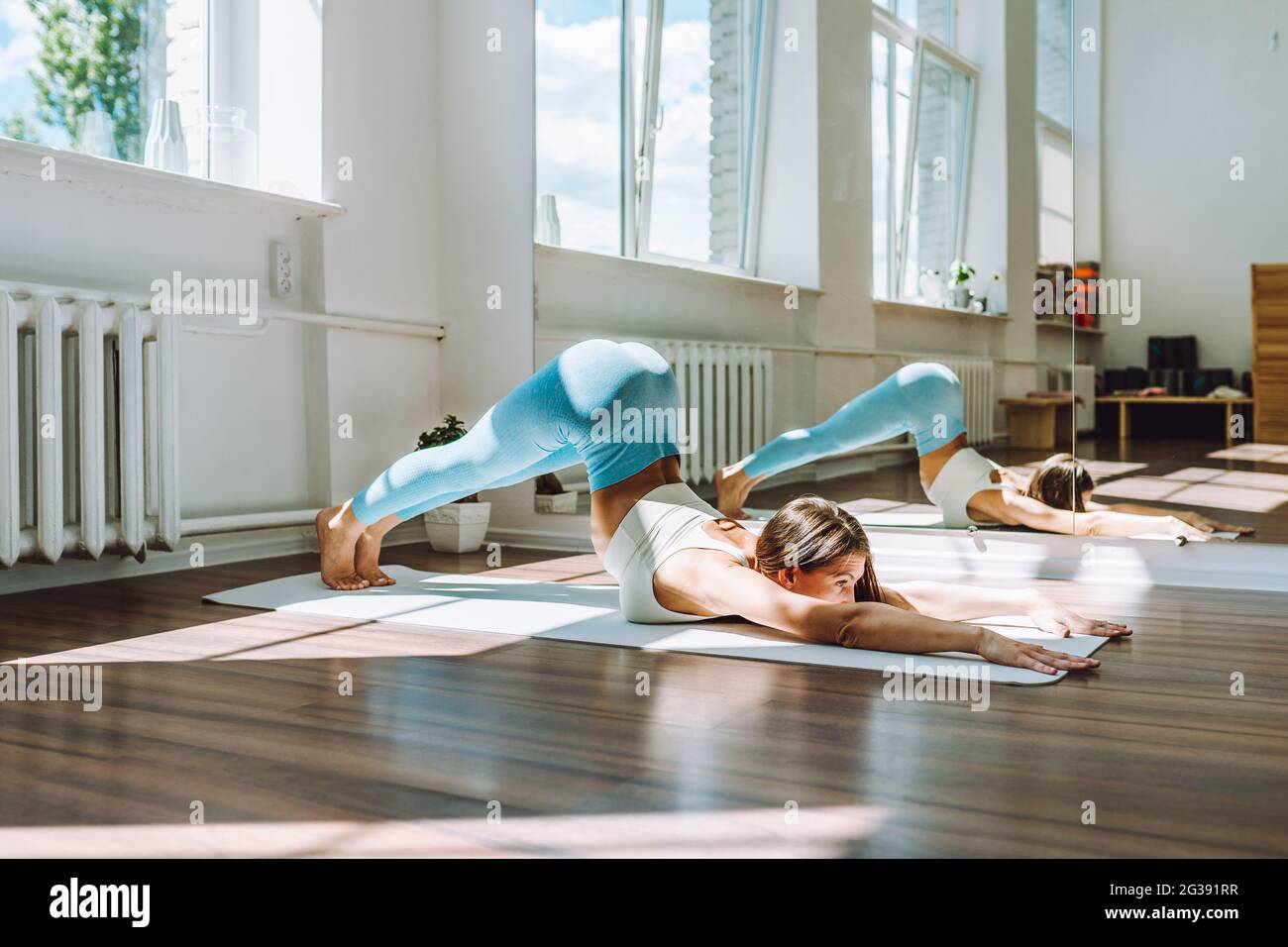 Young female do complex of stretching yoga exercises on floor in light ...