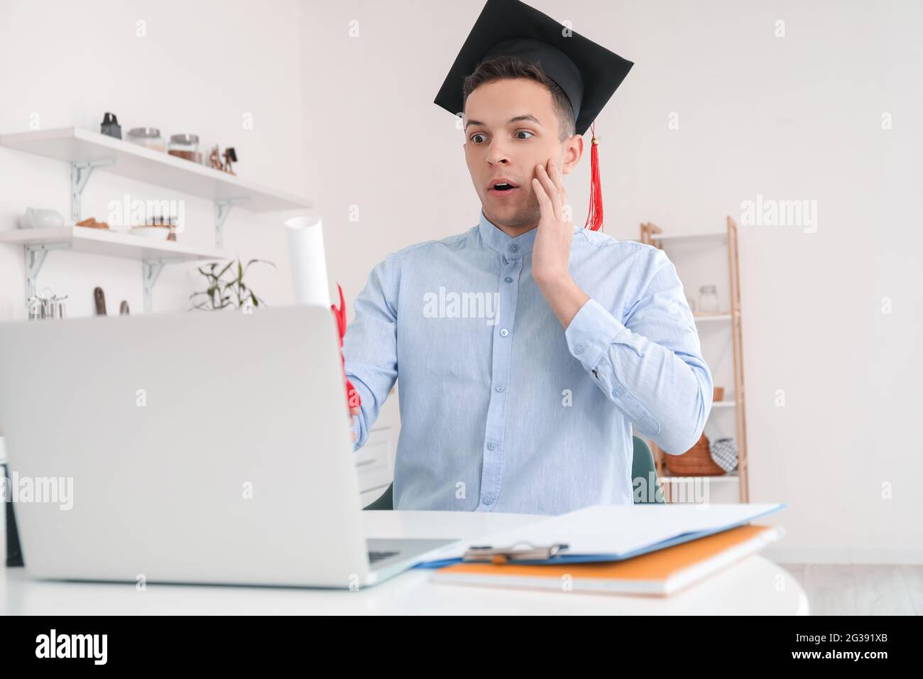 Surprised male student on his graduation day at home. Concept of online ...