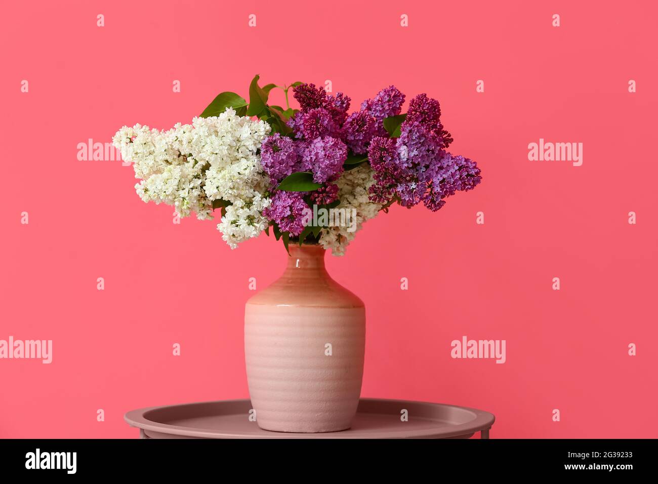 Vase with lilac flowers on table near color wall Stock Photo - Alamy