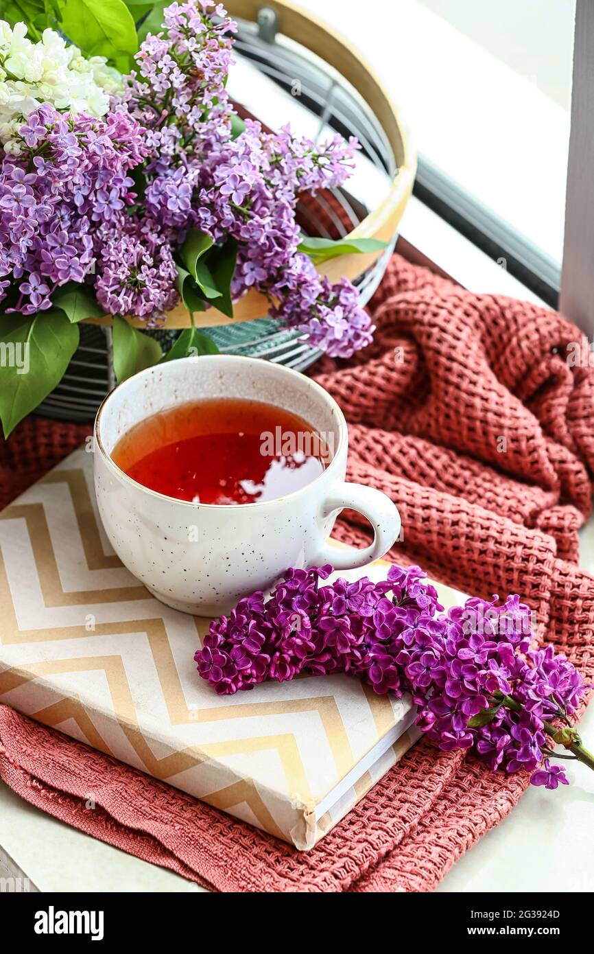 Lilac flowers with cup of tea on windowsill Stock Photo - Alamy