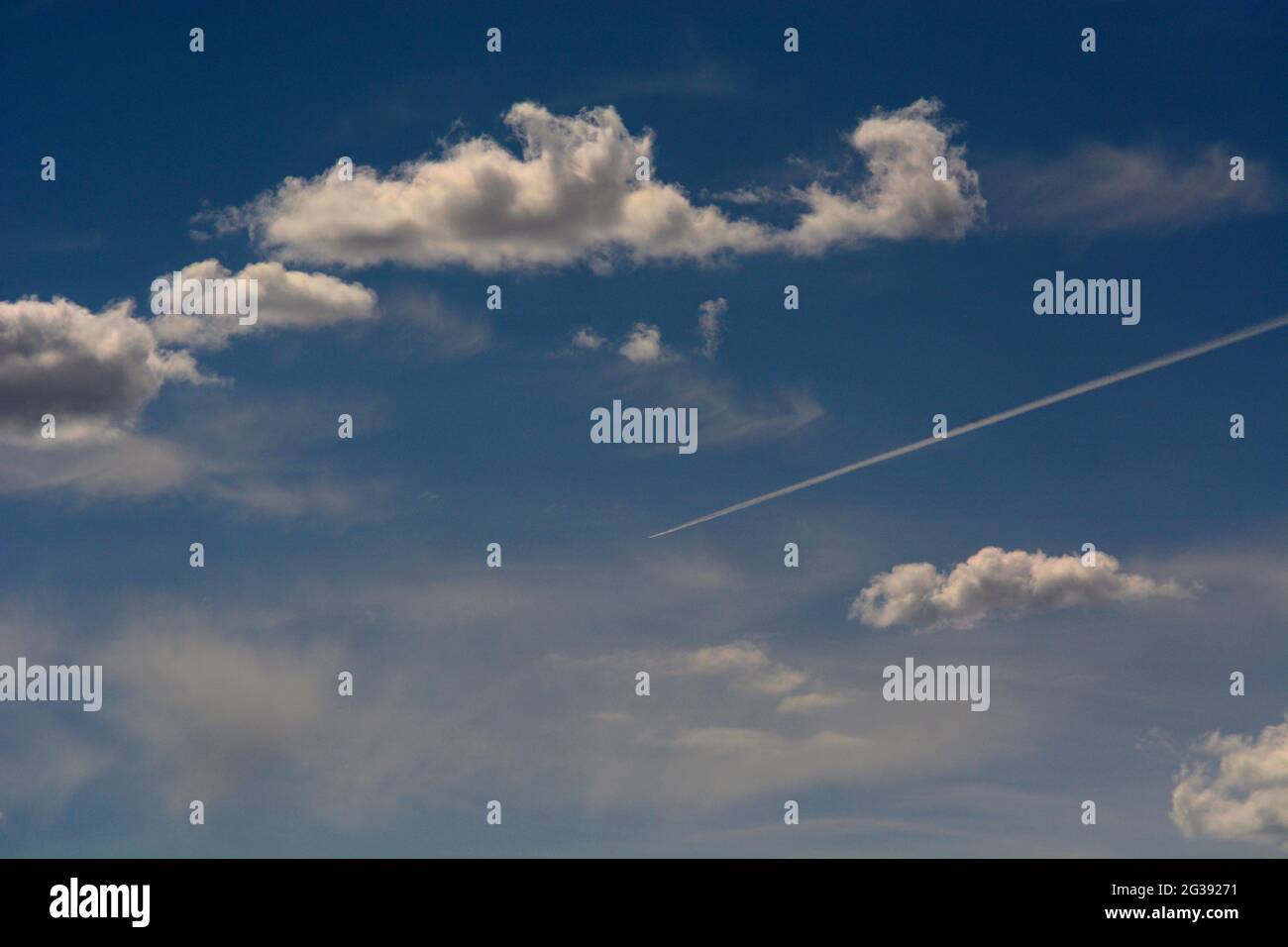 A passenger jet airplane leaves along contrail or vapor trail as it ...