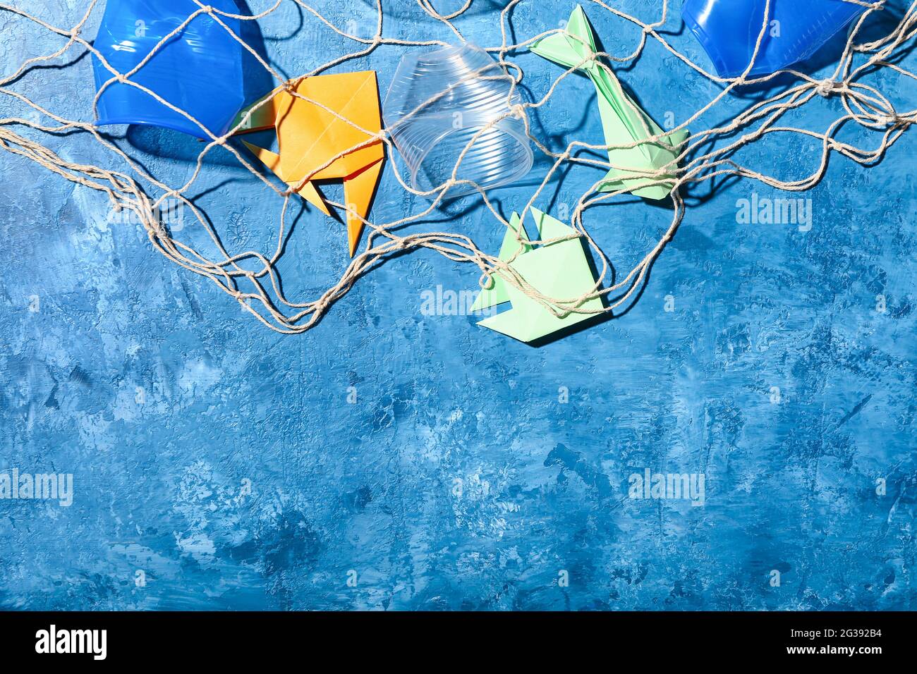 Net with paper fishes and garbage on color background. Ecology concept ...