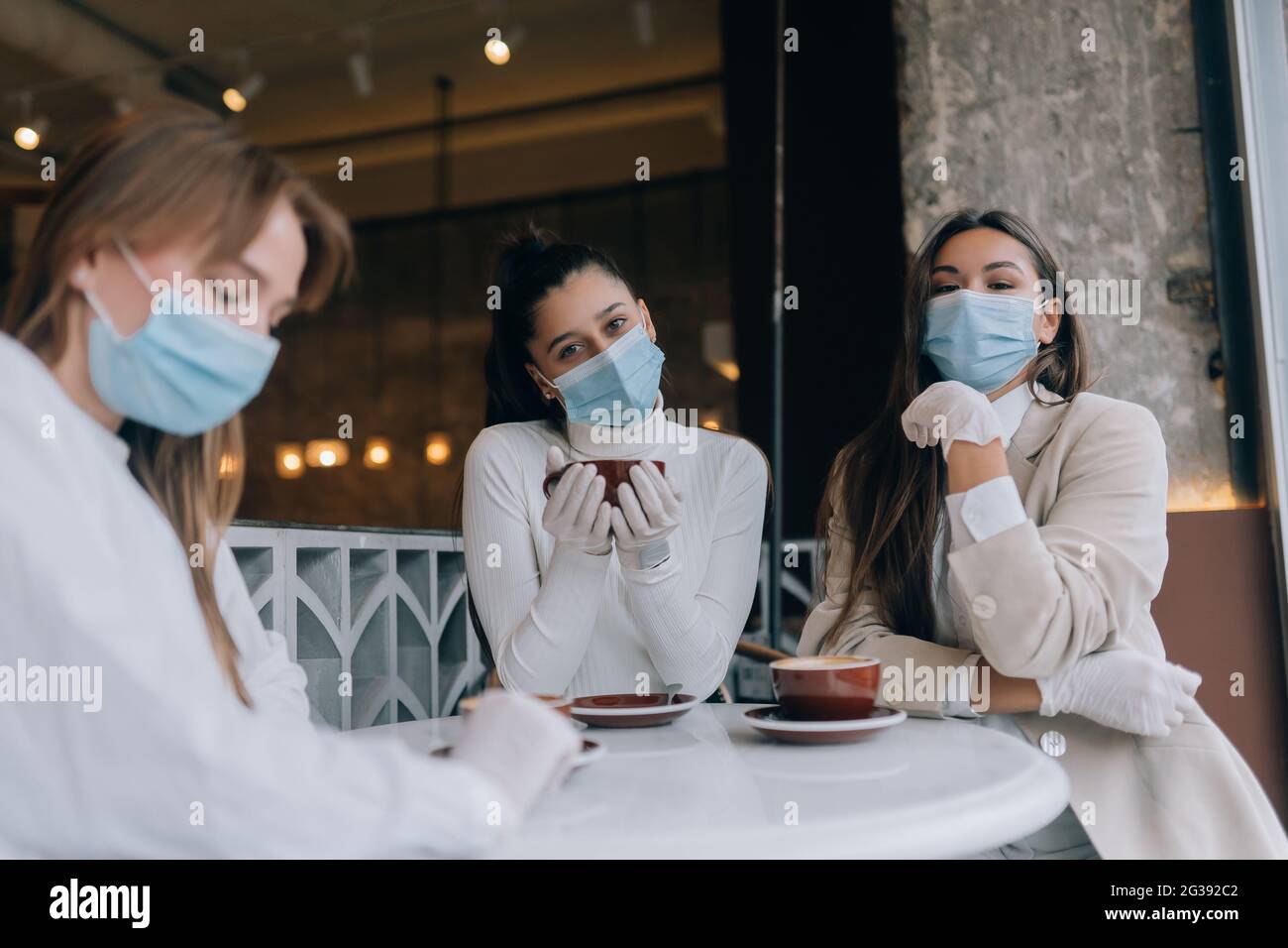 Friends girls met in a cafe. Wear medical protective masks Stock Photo ...