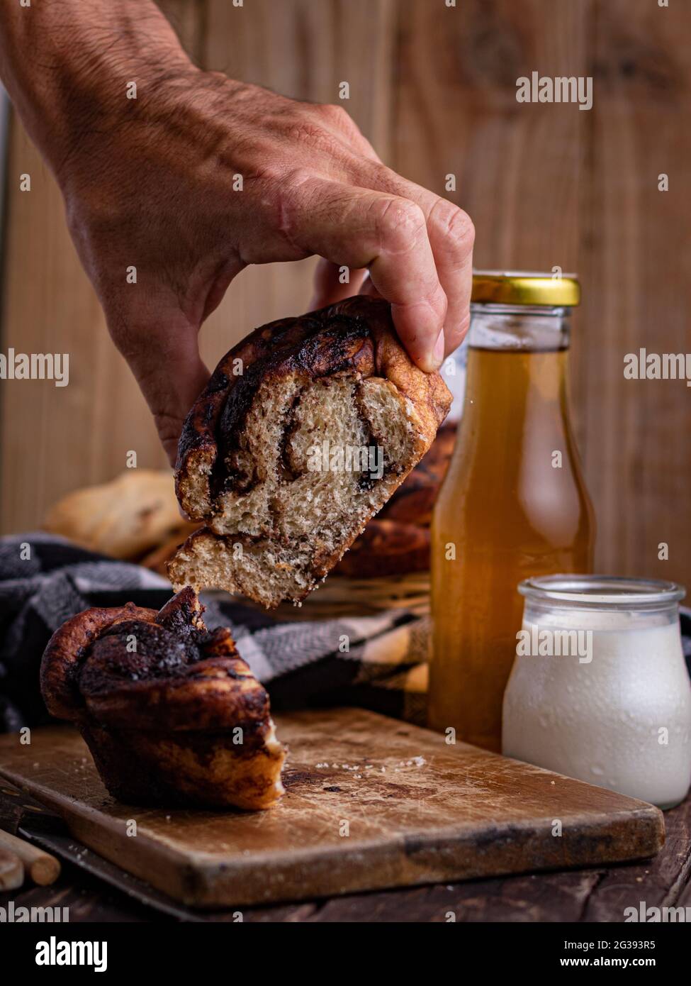Closeup of a hand holding a tasty cookie with bowls of honey and milk ...