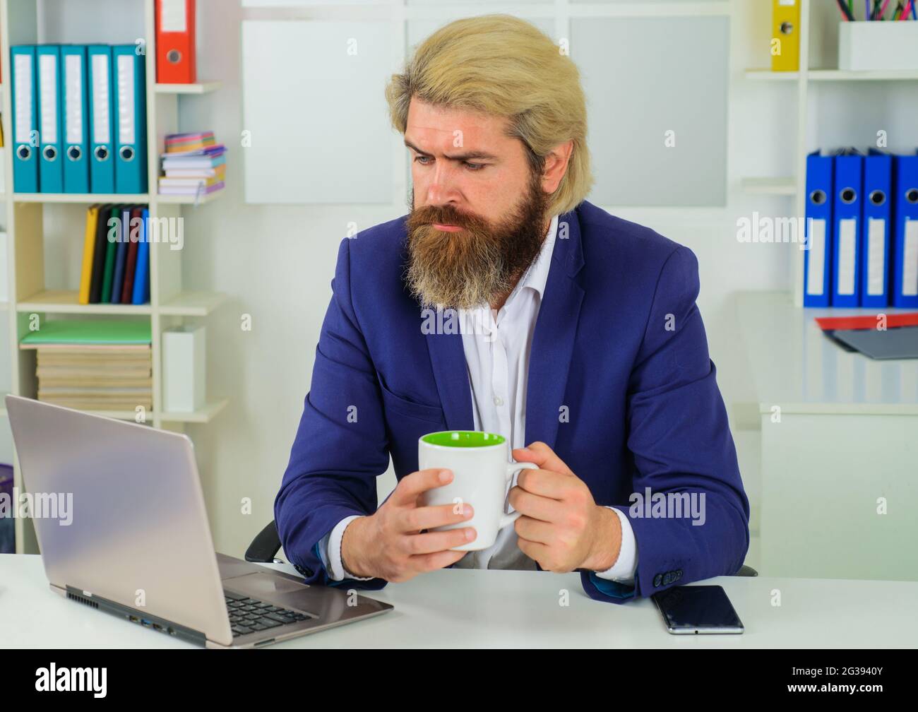Serious businessman in suit drinking coffee. Business man in office ...