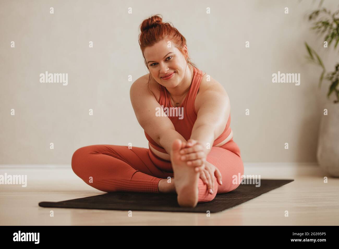 Plus size woman stretching in yoga studio. Female in sports clothing ...