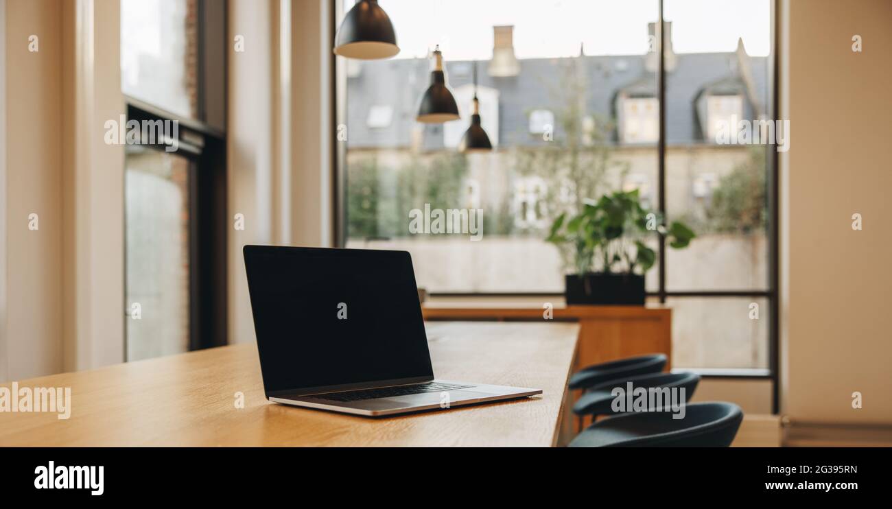 Laptop with blank screen on table in empty board room. Empty conference ...