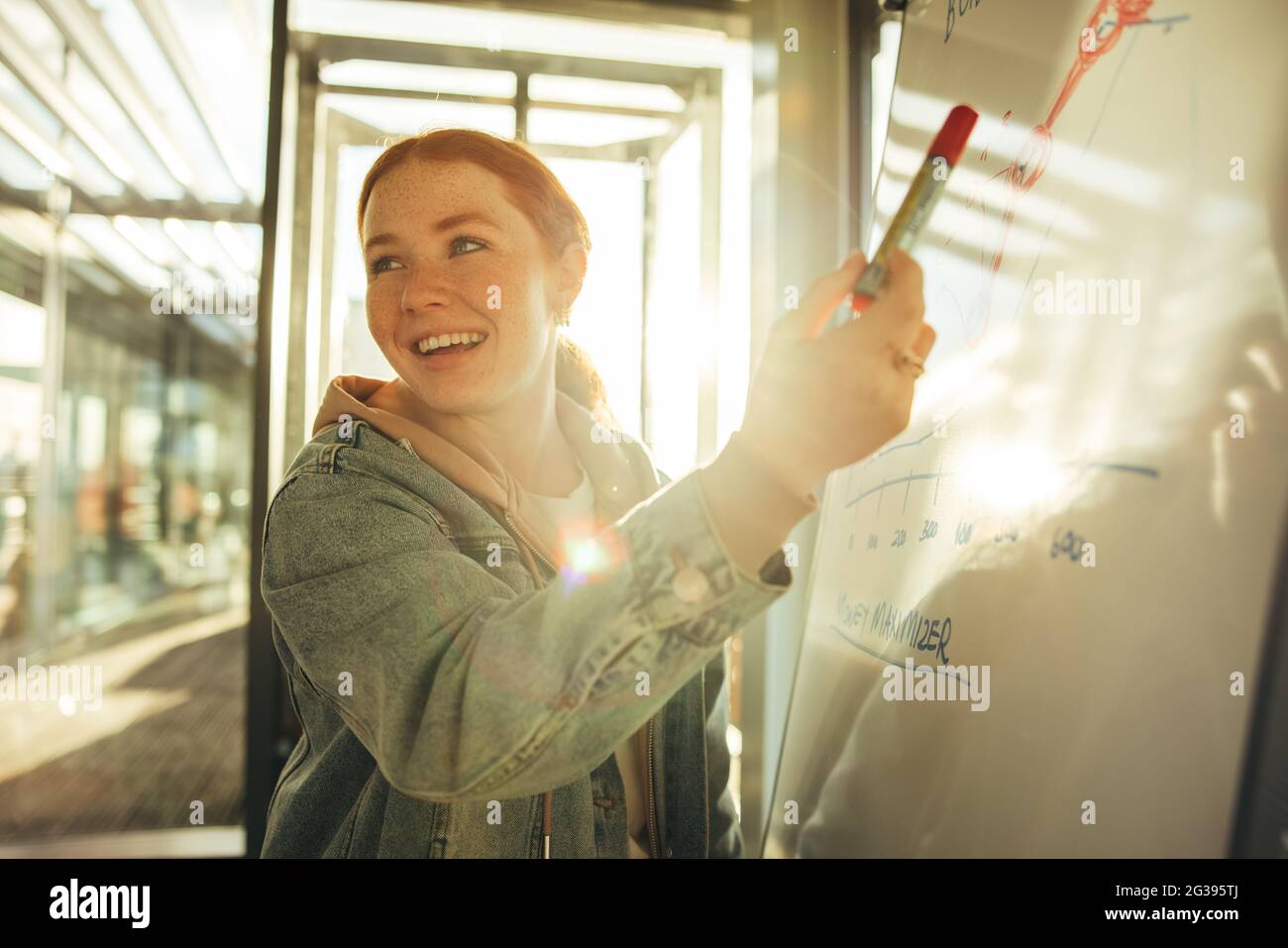 Female student pointing at whiteboard and smiling. Happy young female ...