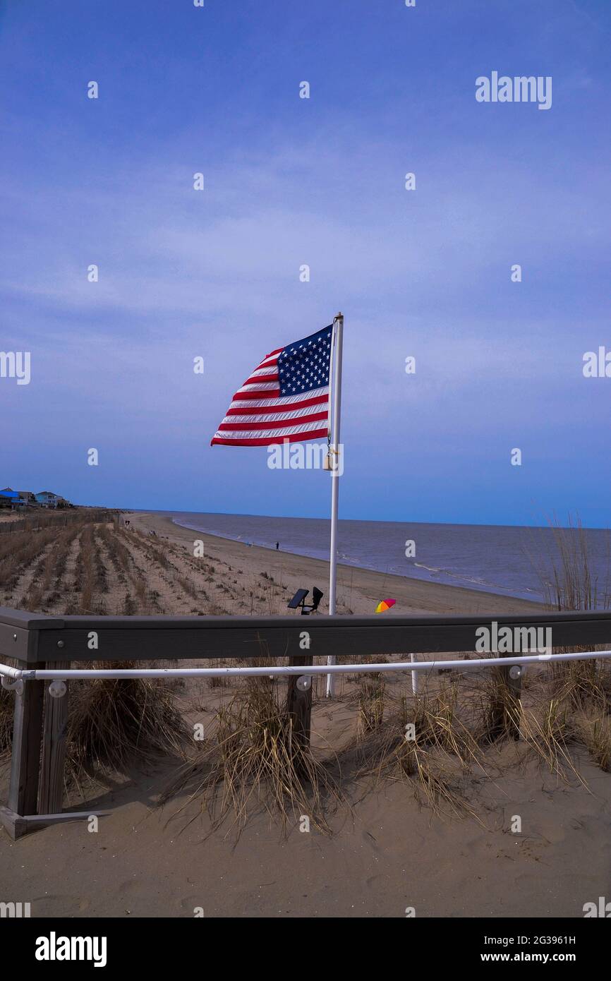 Red, white and blue American Flag waves in the wind over sandy ...