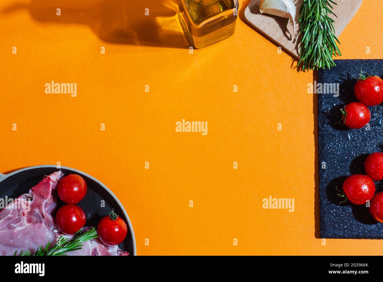 Top view of a pork chop with cherry tomatoes, rosemary, garlic, and ...