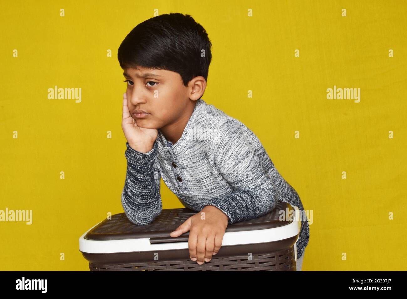 Indian little boy leaning on a basket and thinking Stock Photo - Alamy