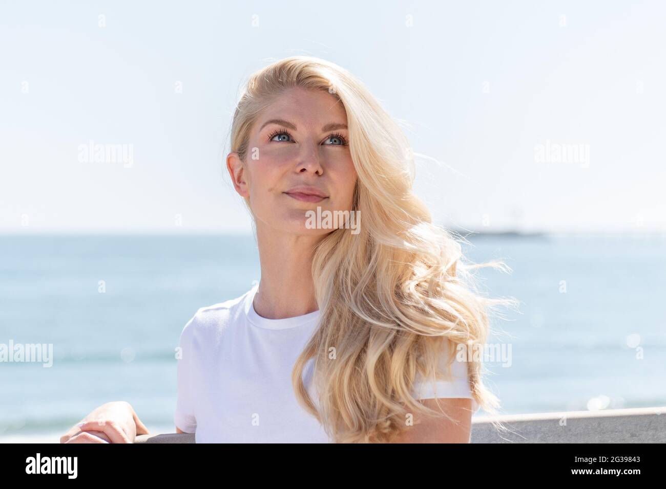 Beautiful blond hair female model looking up to right toward the sunny ...