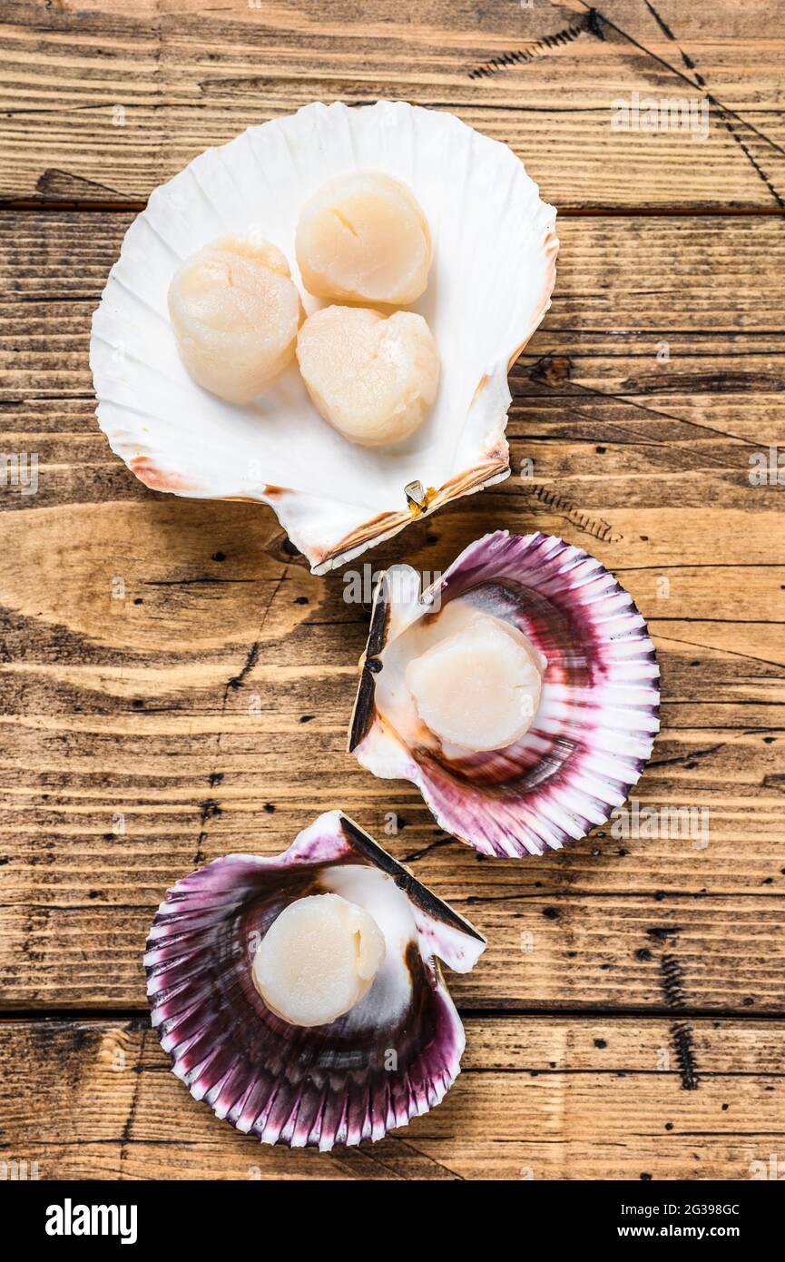 Raw seafood scallops meat on a shells. Wooden background. Top view ...