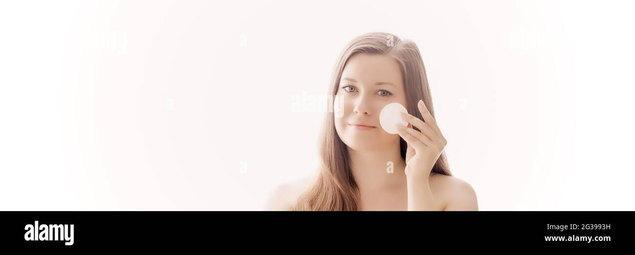 Beautiful woman with cotton pad, perfect skin and shiny hair as make-up ...
