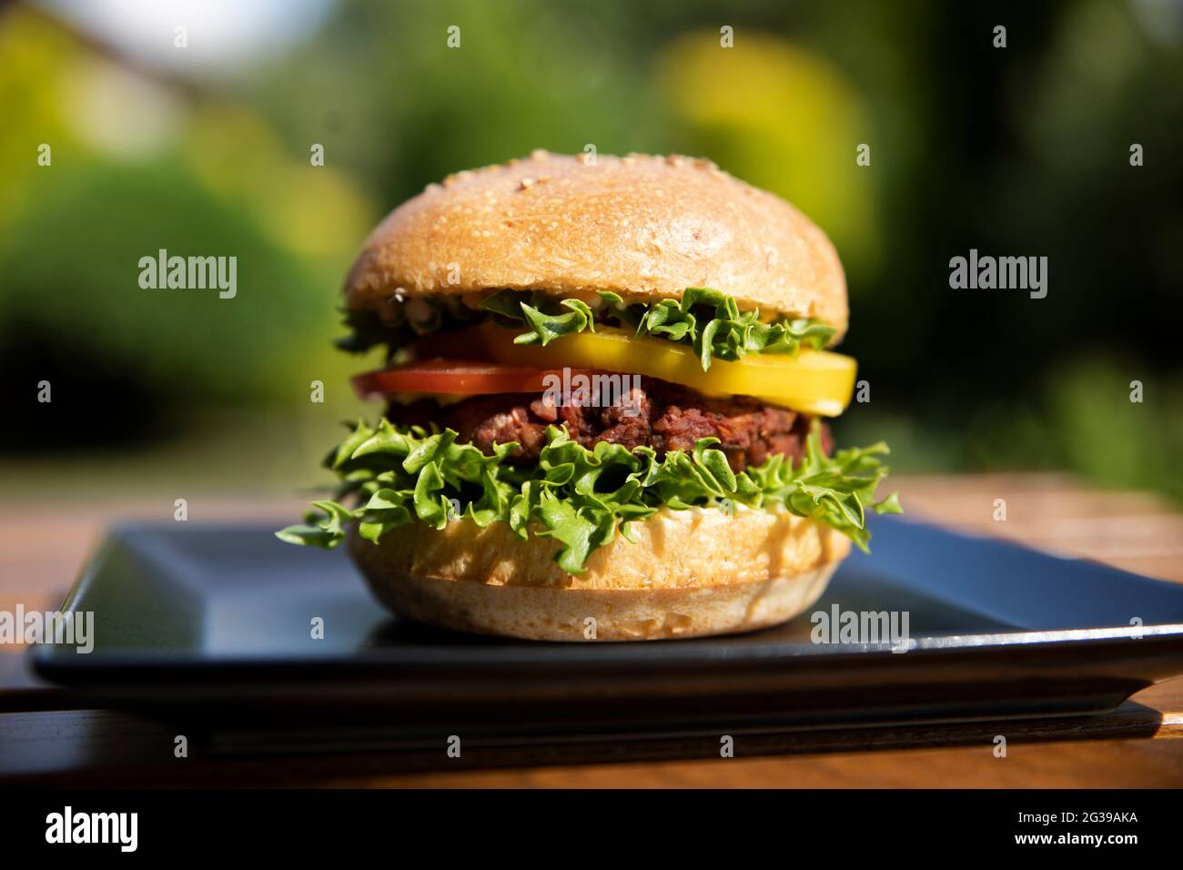 Vegetarian vegan bean burger on a black plate outside Stock Photo - Alamy