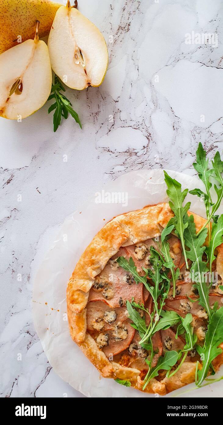 Cutted pears and pear and gorgonzola cheese galette with green rucola ...