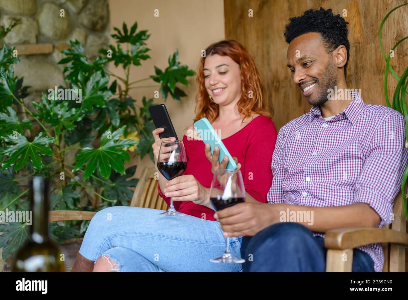 multiethic couple enjoying a glass of wine together outdoor sitting on ...