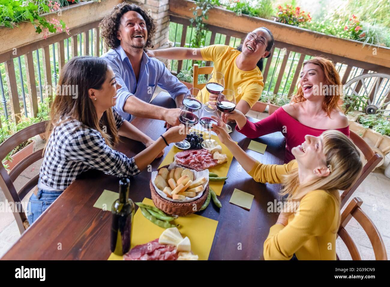 multiethic group of people enjoying wine together outdoor sitting on a ...