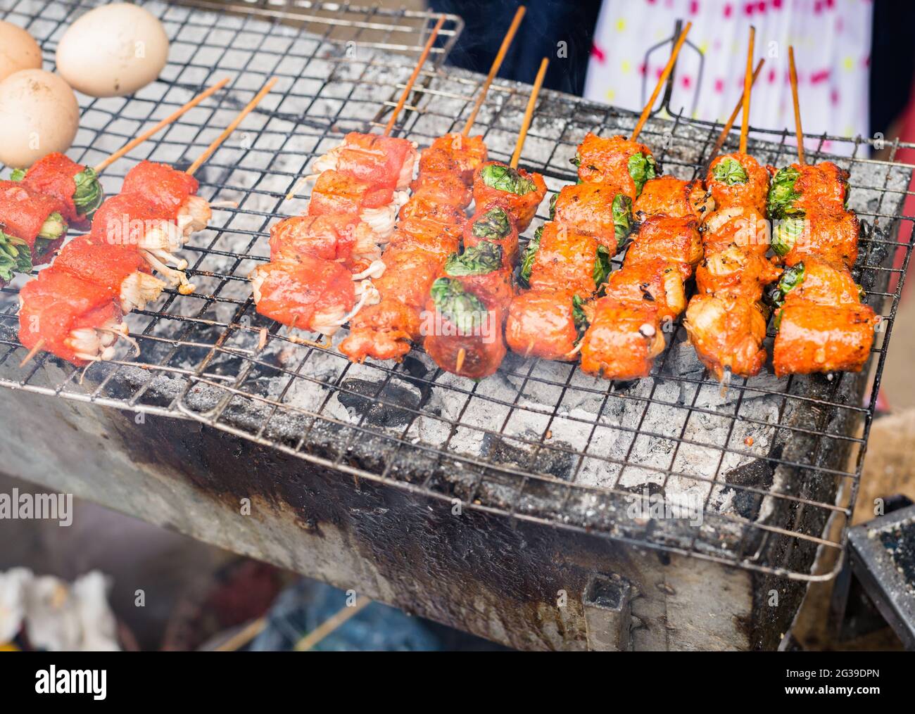 Skewers of various meats cooking on a BBQ like structure in rural ...
