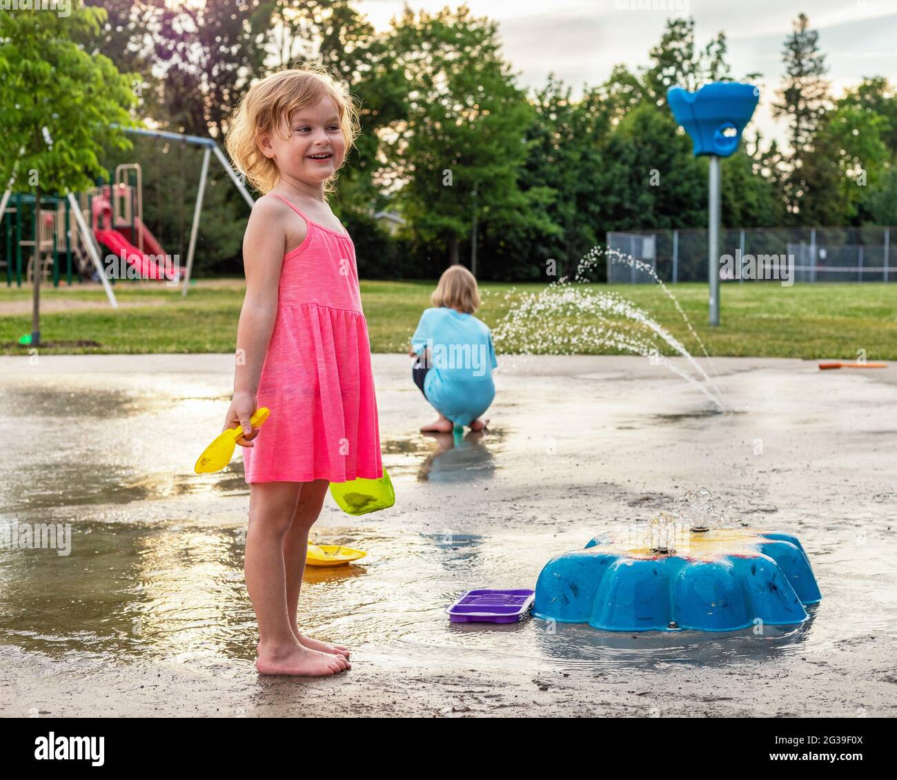 Little smiling child playing with water and toys at splash pad in the ...