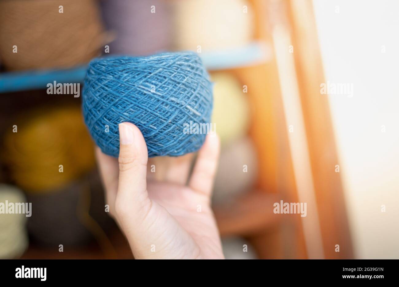 Female hand holding the dark blue yarn ball with the earth tone yarn in ...