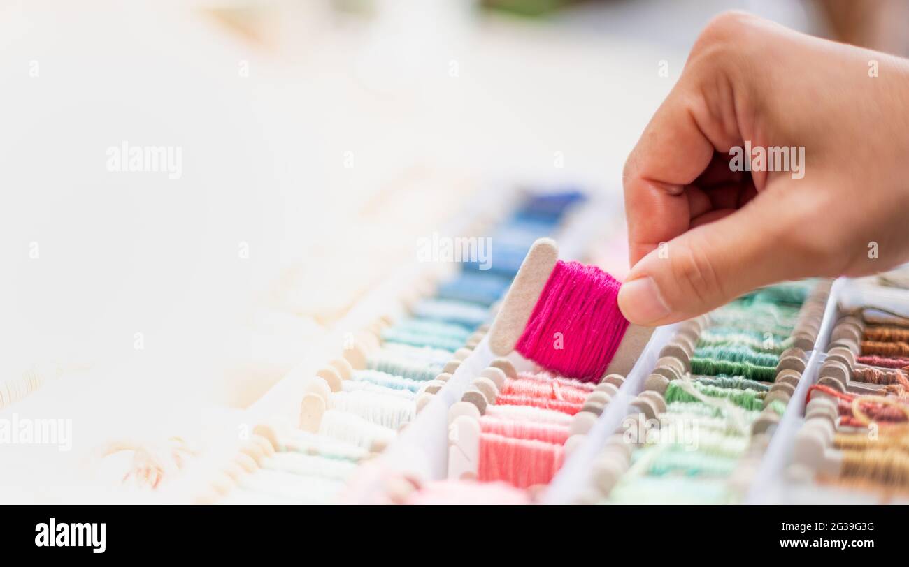 Close up hands of tailor woman holding vivid pink threads and different ...