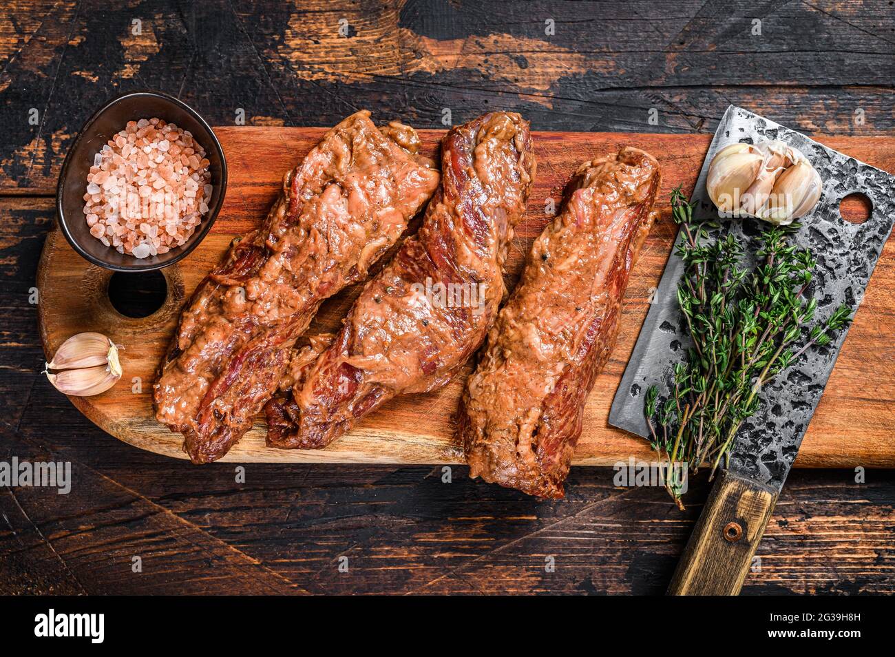 Raw Marinated skirt steaks in bbq sauce on a wooden cutting board with ...