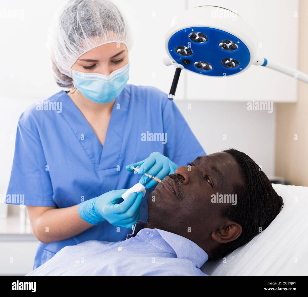 Skilled cosmetologist performing face contouring injections to man ...