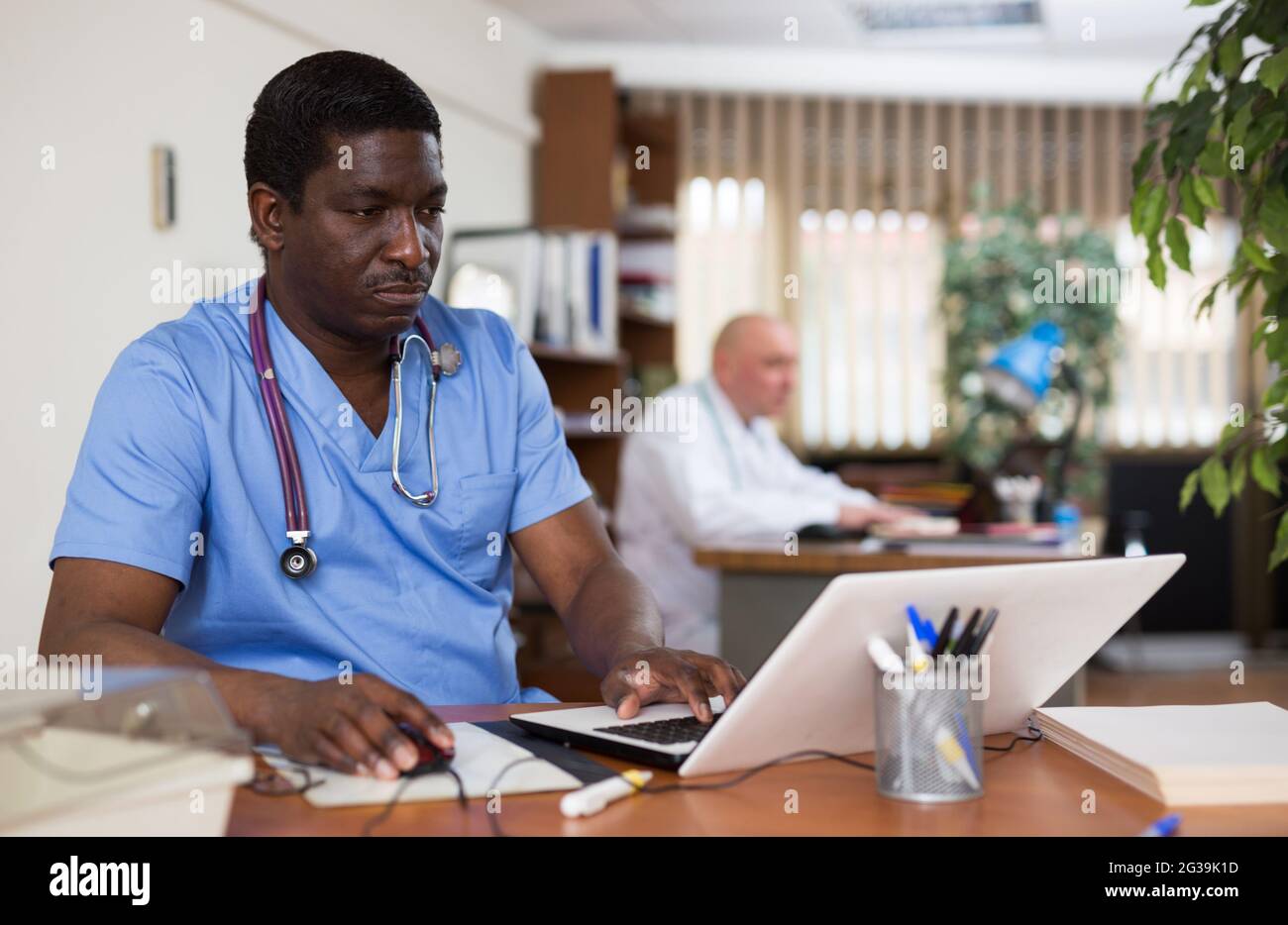 Focused african american doctor works at a computer in an office Stock ...