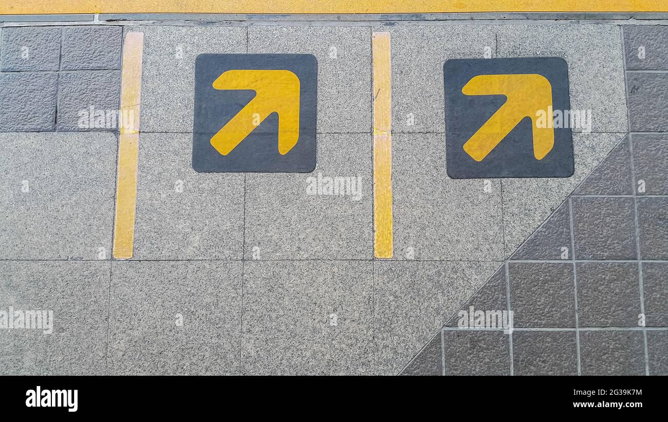 arrow sign in yellow color painted on black on the waiting zone for ...