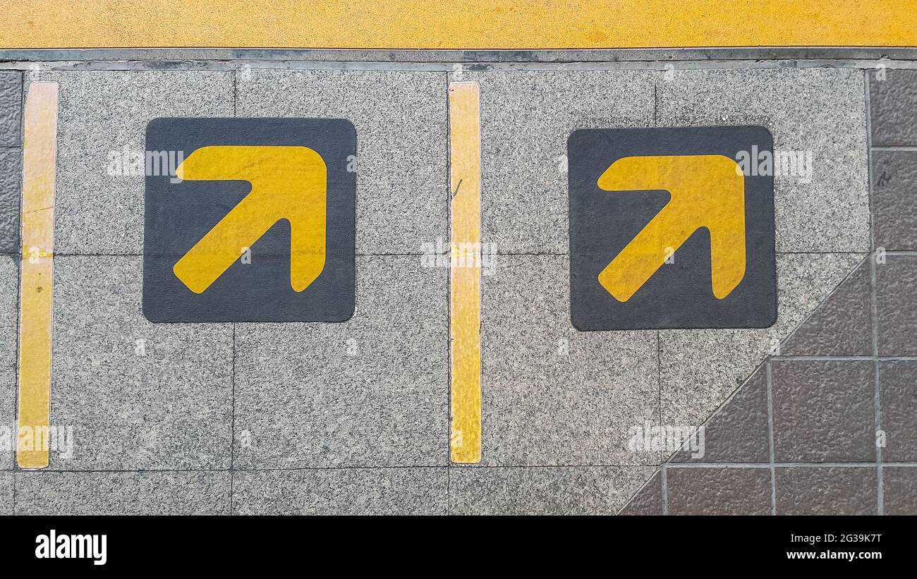 arrow sign in yellow color painted on black on the waiting zone for ...