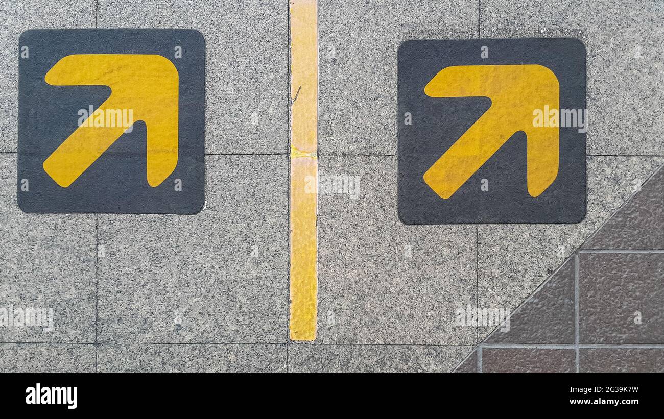 arrow sign in yellow color painted on black on the waiting zone for ...