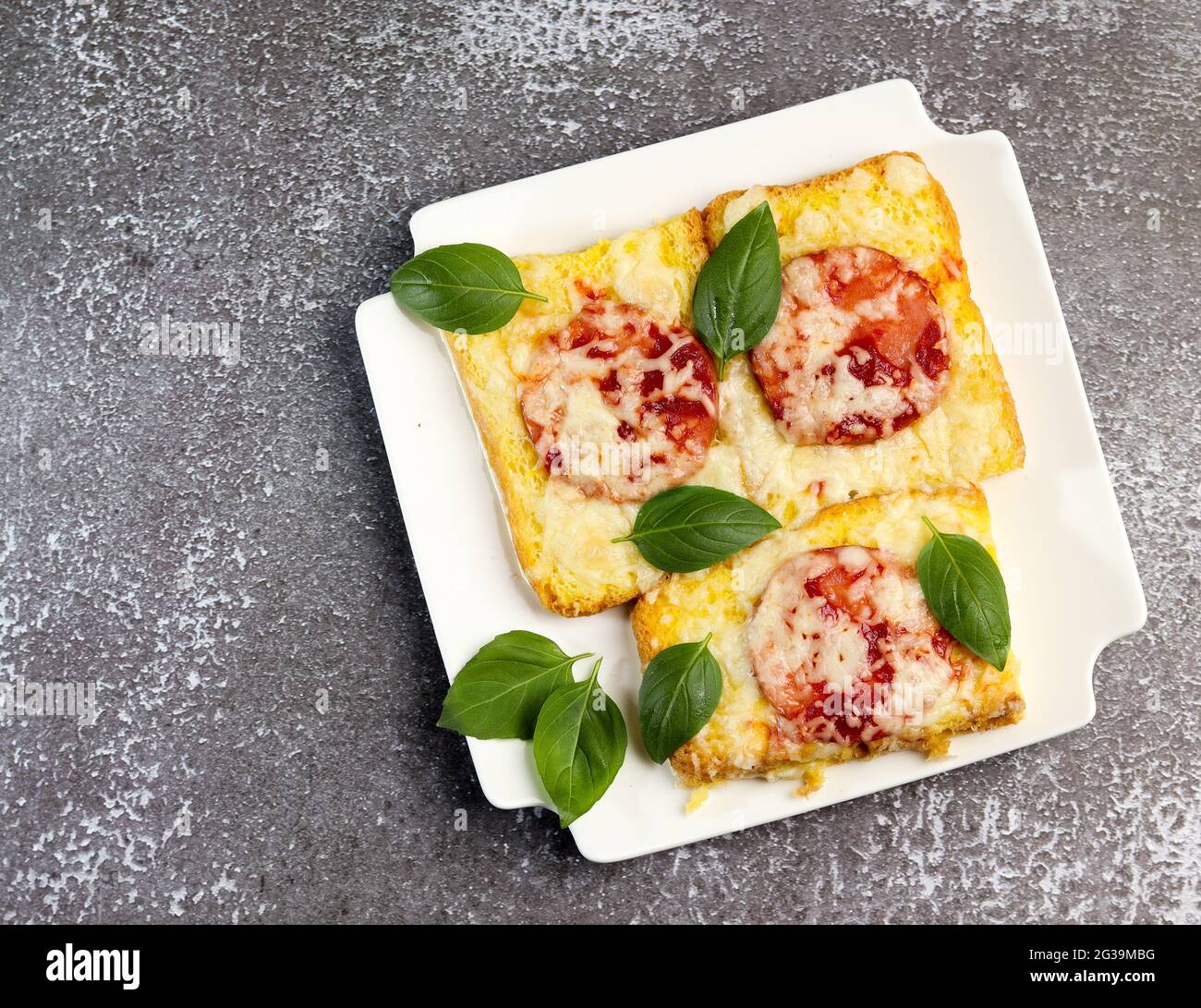 Baked open faced sandwiches with cheese, herbs and sausage on a white ...